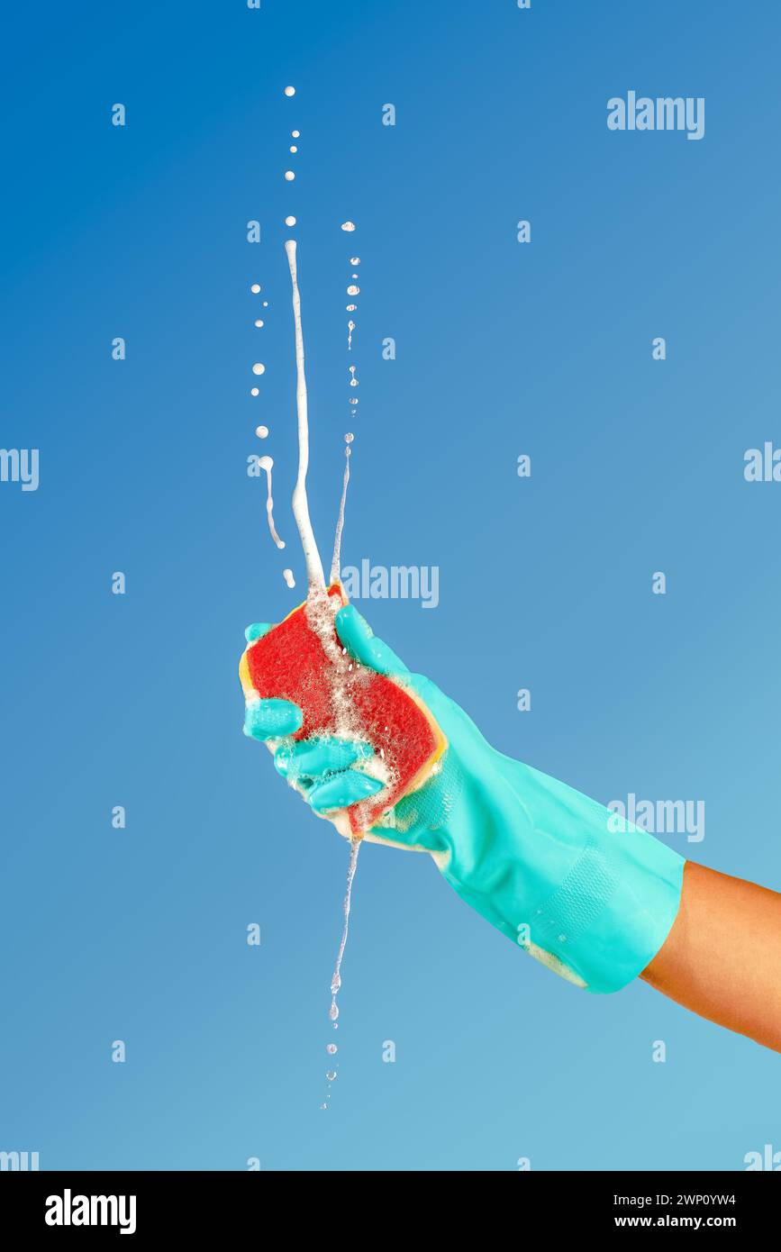 a rubber cyan glove squeezes a red sponge with a lot of drops Stock ...