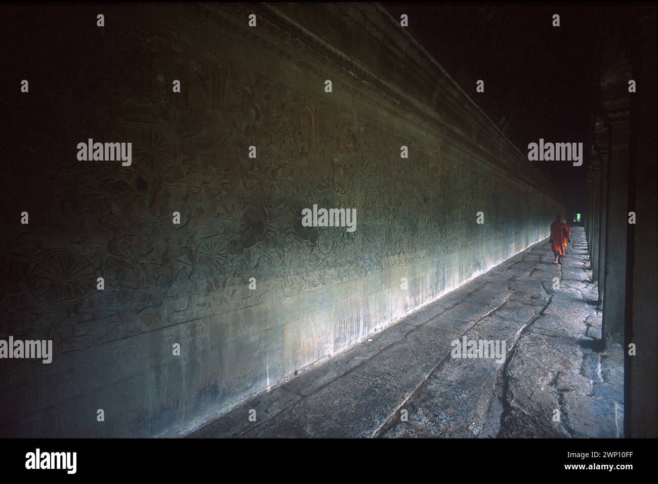 Monk walking in gallery with relief of battle scenes from the Ramayana ...