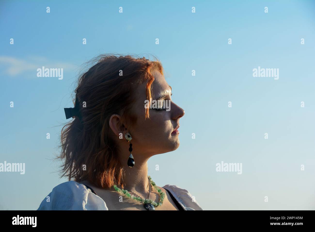 Profile of a pretty young woman, face to the sun, with sky Stock Photo ...