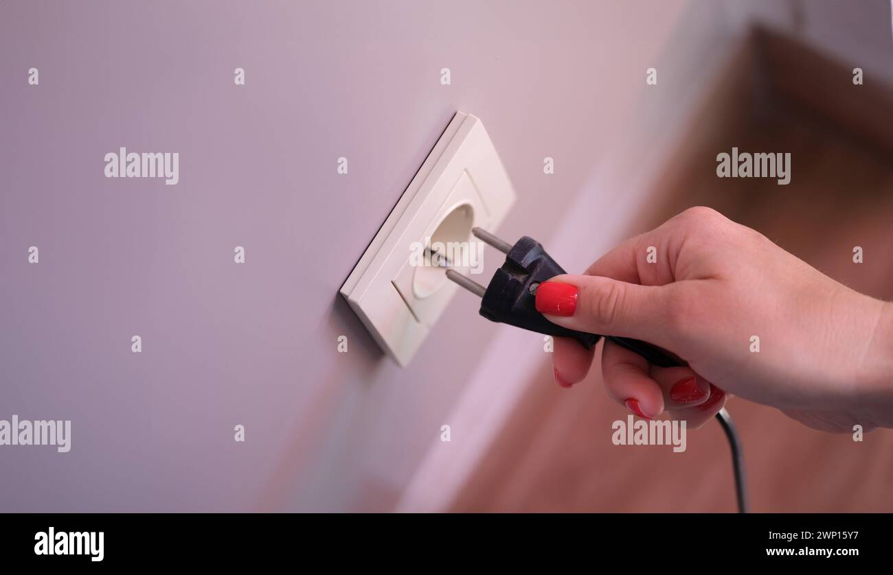 Hand inserts plug into socket closeup. Use of promising energy in home ...