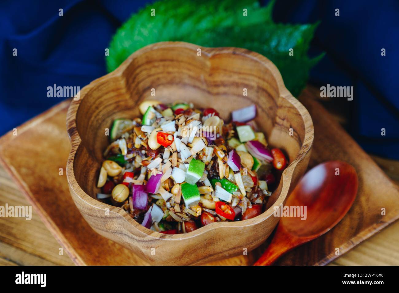 A bowl of food with a spoon in it. The bowl is wooden and has a flower ...