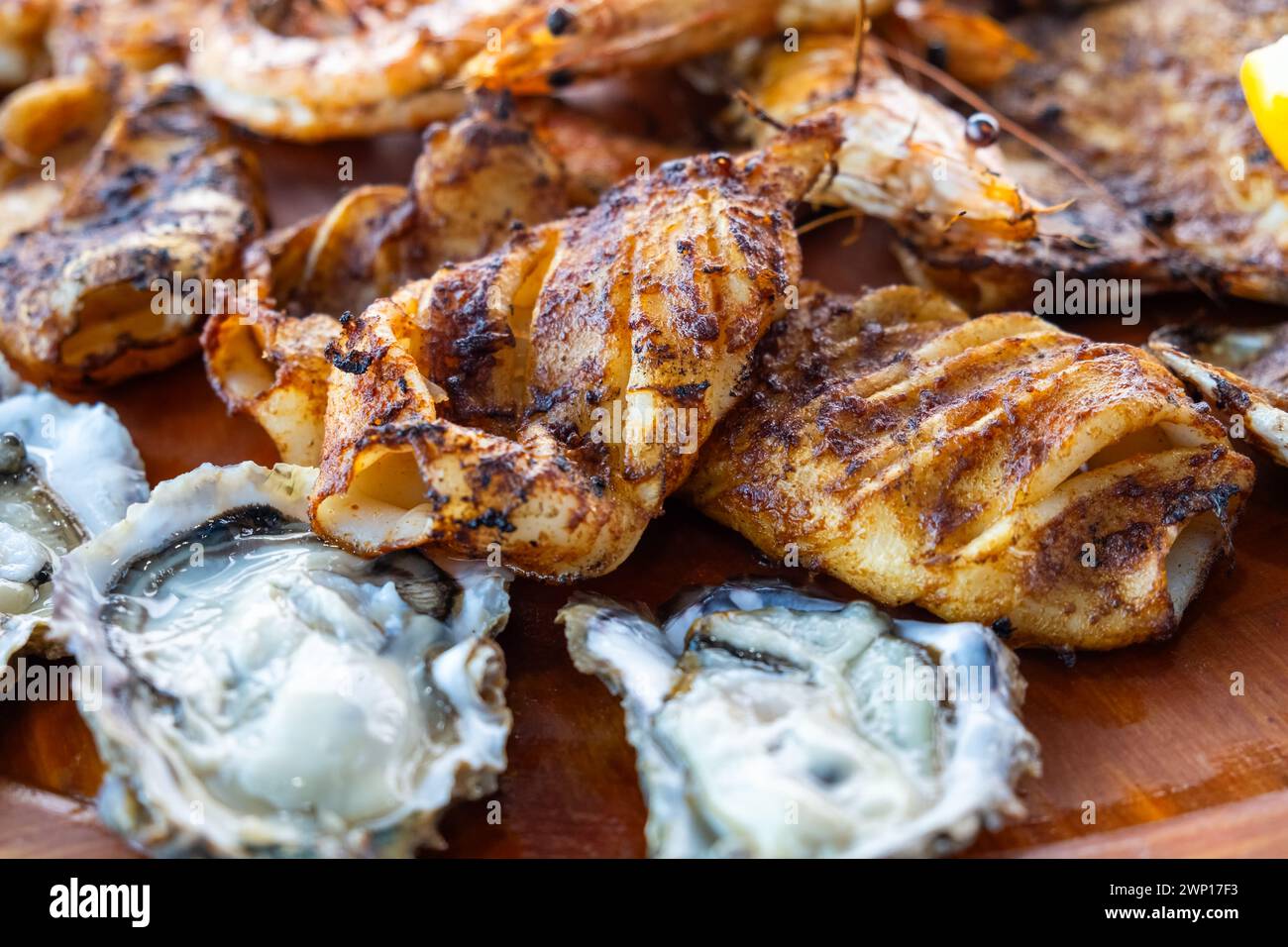 Grilled squids and raw oysters on seafood wooden plate. Charcuterie ...