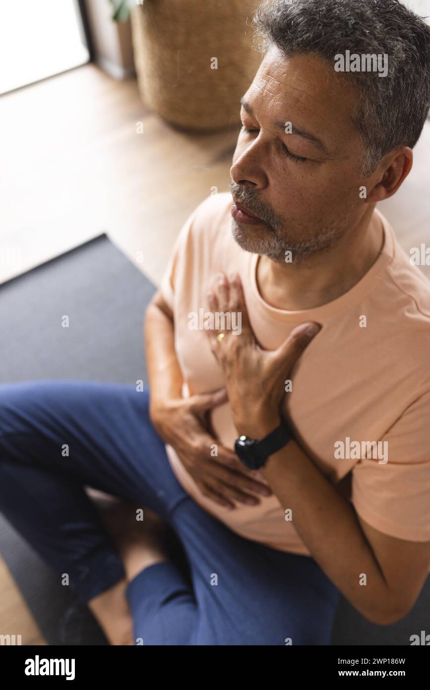 Biracial senior man meditates with eyes closed, hand on chest Stock ...