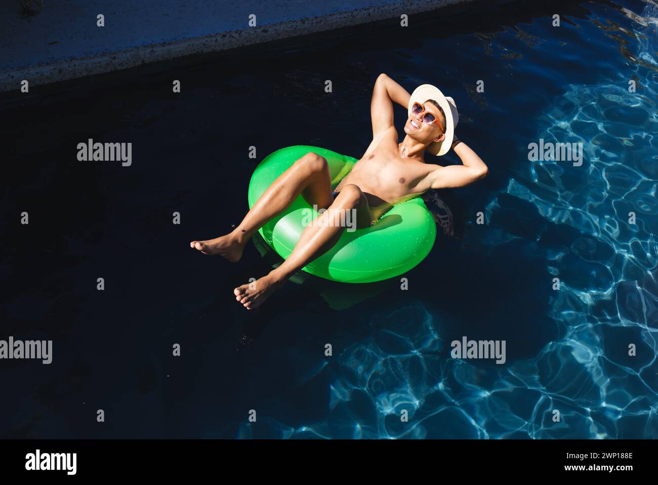 A Young Asian Man Relaxes On A Green Float In A Pool Wearing A White