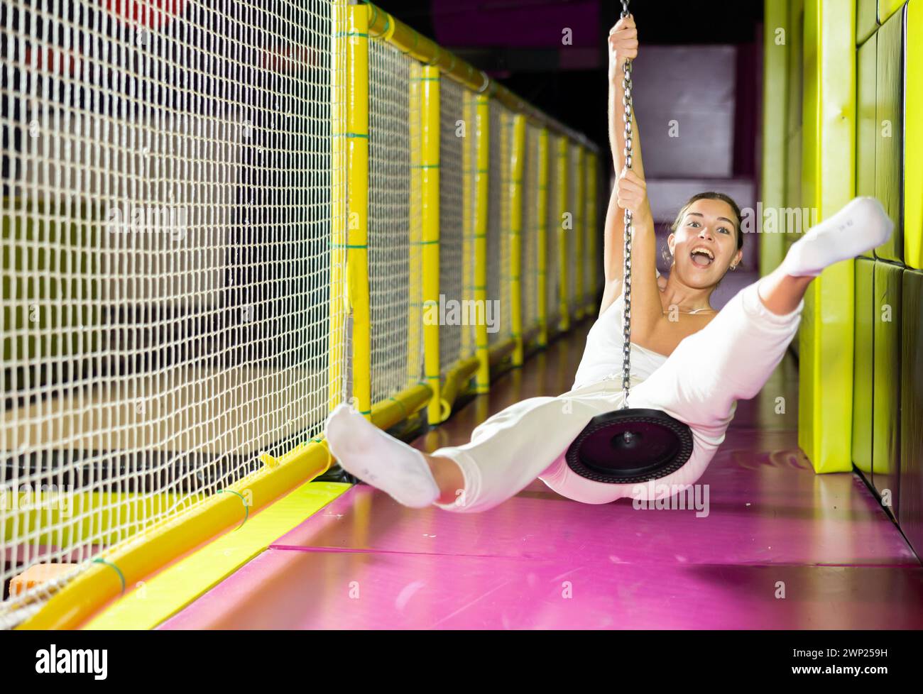 Cheerful young girl riding zip line in indoor amusement center Stock ...