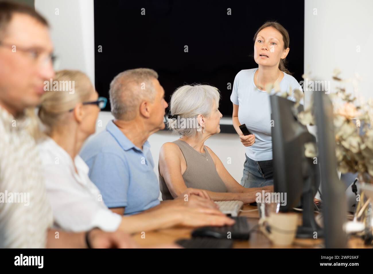 Woman teacher teaching elderly people how to use computer Stock Photo ...