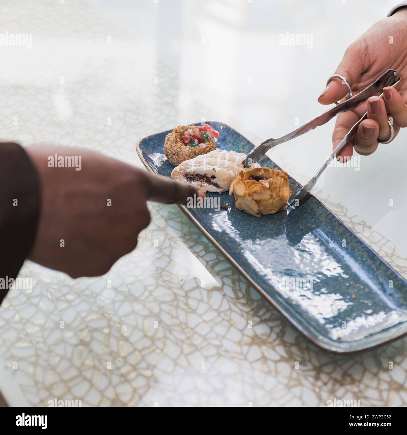 Photo close-up of a customer's hand pointing at a chosen pastry, as the ...