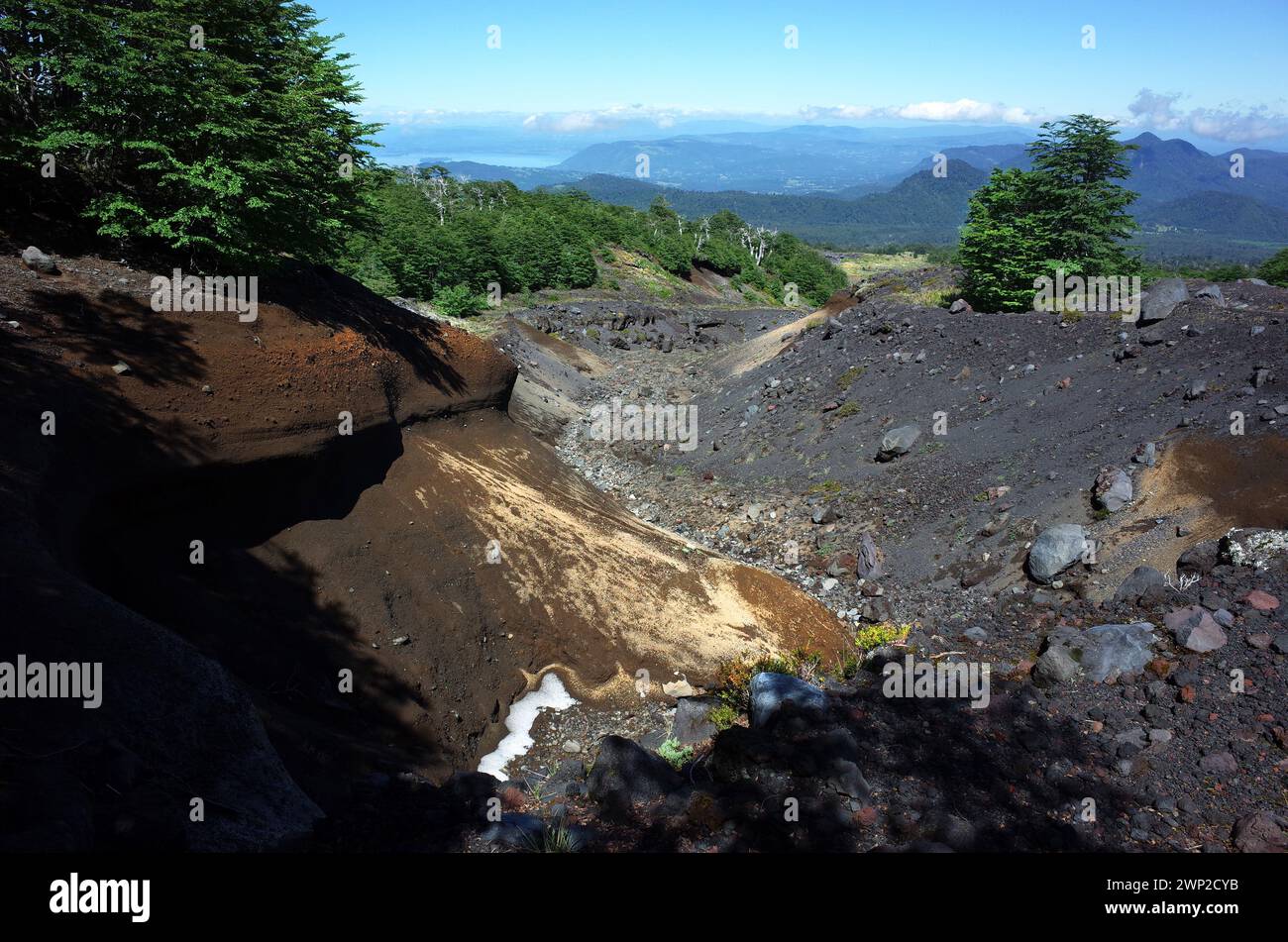 Dark ash and frozen lava ravine on side of Villarrica volcano along ...