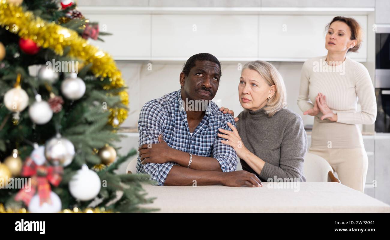 Quarrel during Christmas celebration. Mom calms her son-in-law while ...