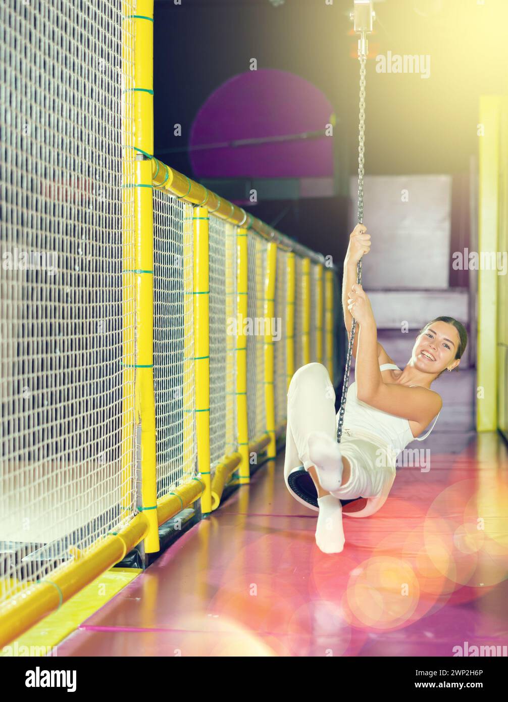 Cheerful girl swinging on indoor zip line at play center Stock Photo ...