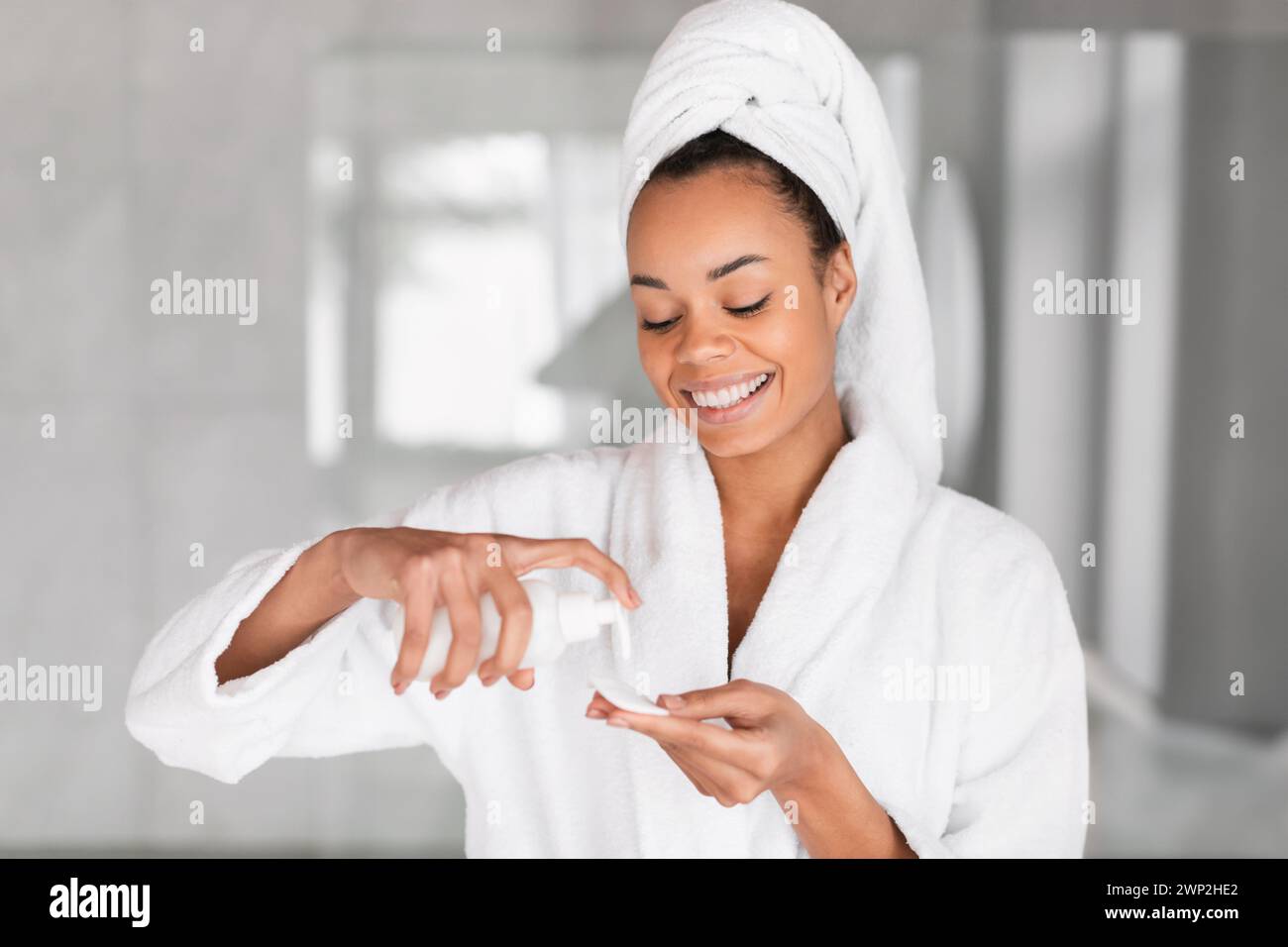 Happy African American woman applying tonic on cotton pad indoor Stock ...