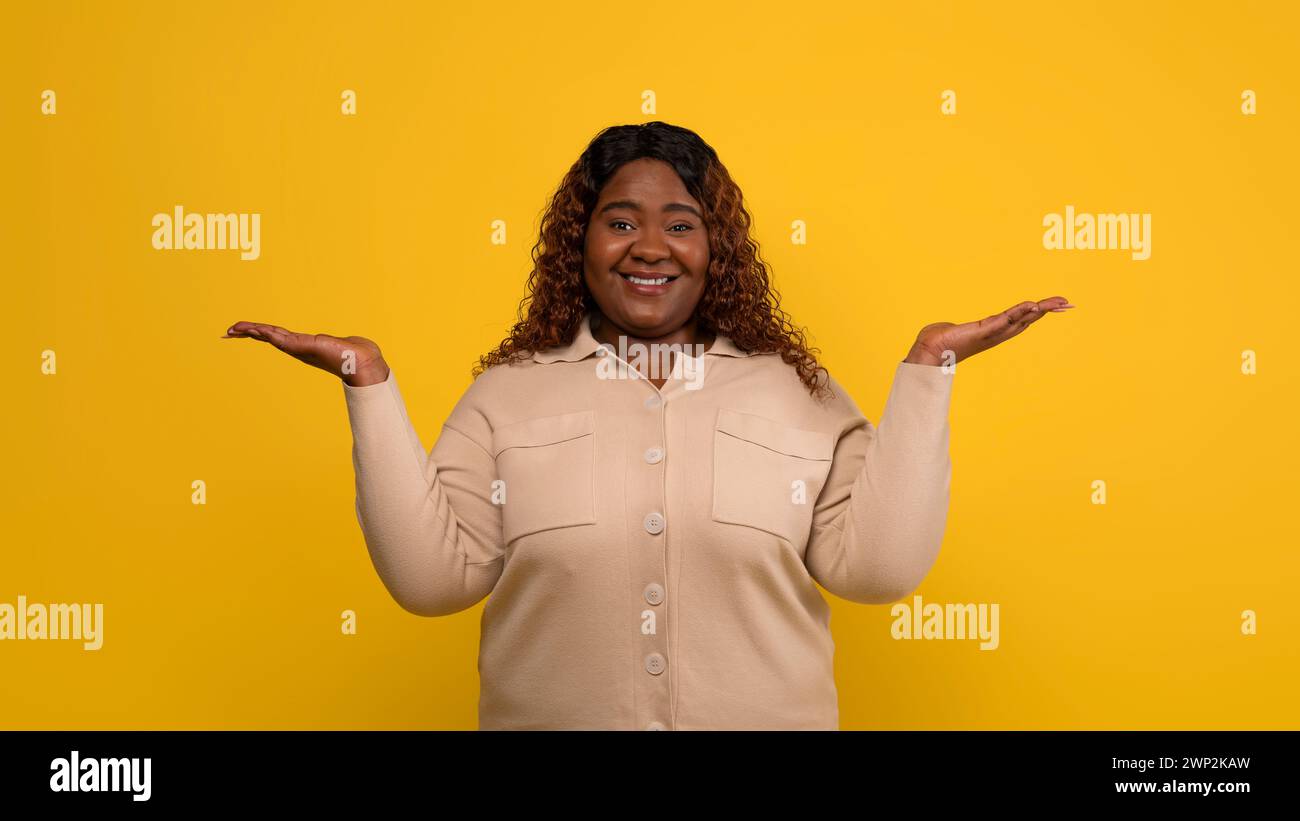 Positive young black woman holding something invisible on her palms ...