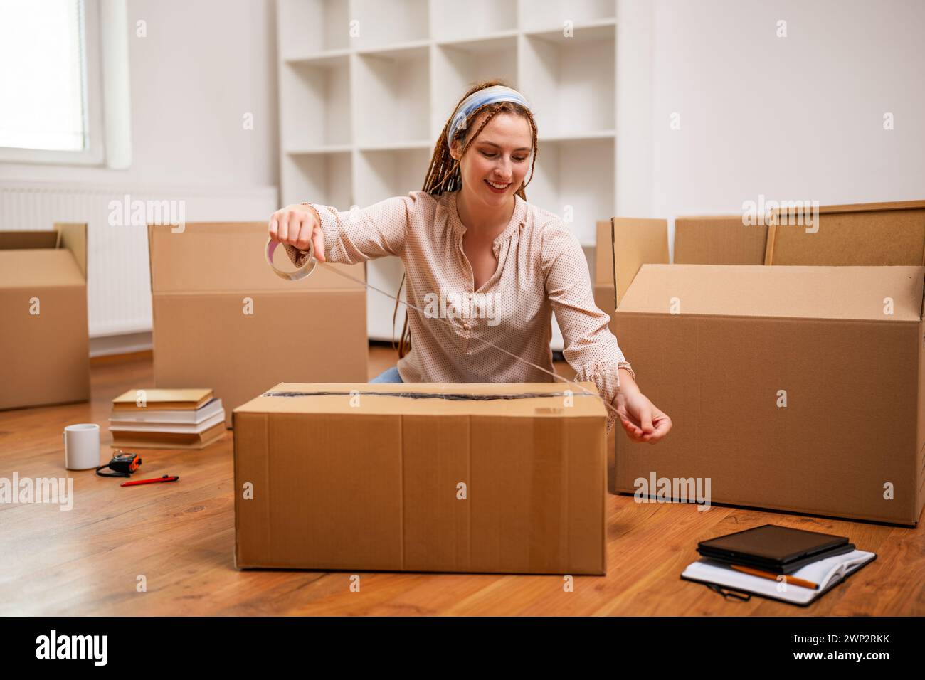 Modern ginger woman with braids moving into new home Stock Photo - Alamy