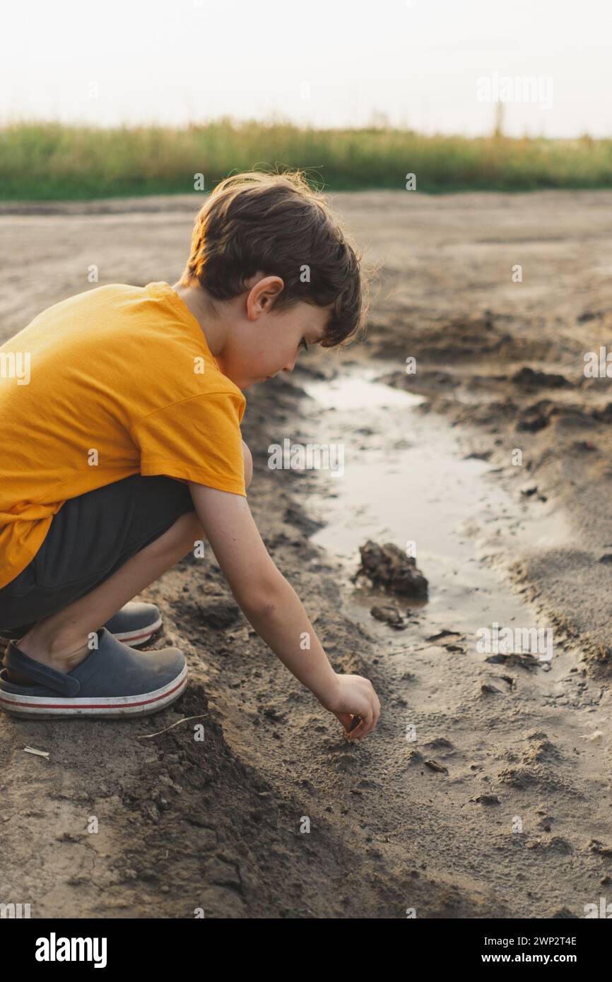 A boy in an plays with mud in the ground in nature. lifestyle Stock ...