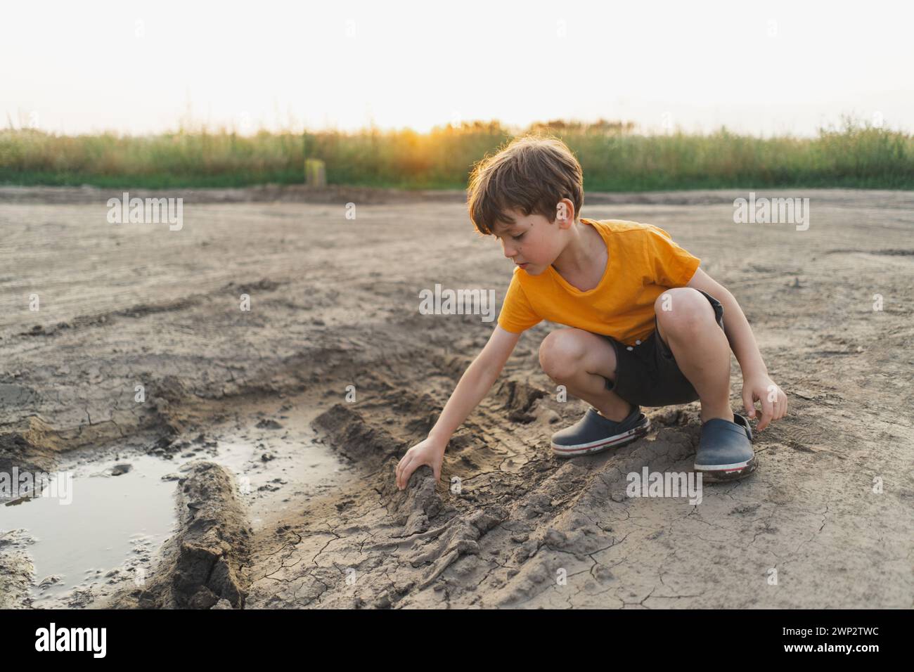 A boy in an plays with mud in the ground in nature. lifestyle Stock ...
