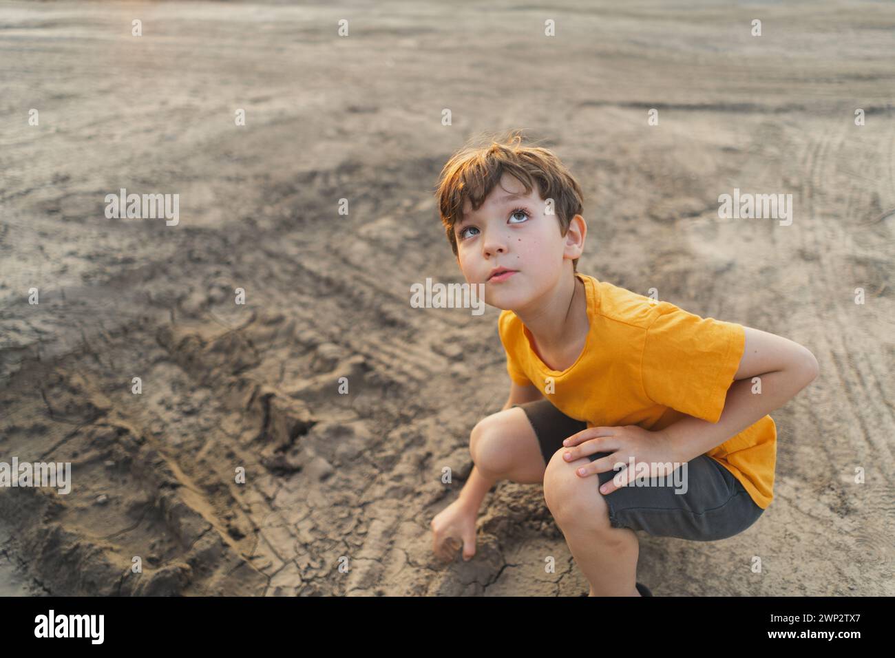 A boy in an plays with mud in the ground in nature. lifestyle Stock ...