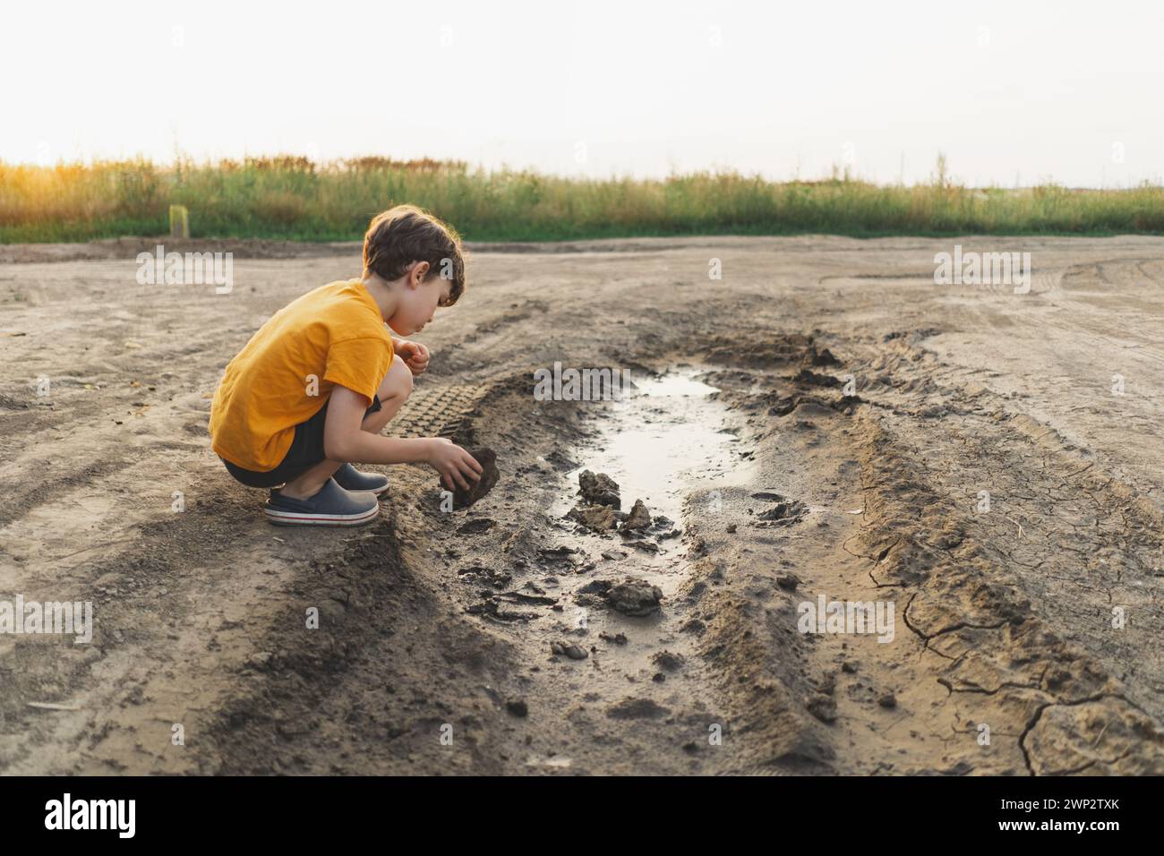 A boy in an plays with mud in the ground in nature. lifestyle Stock ...