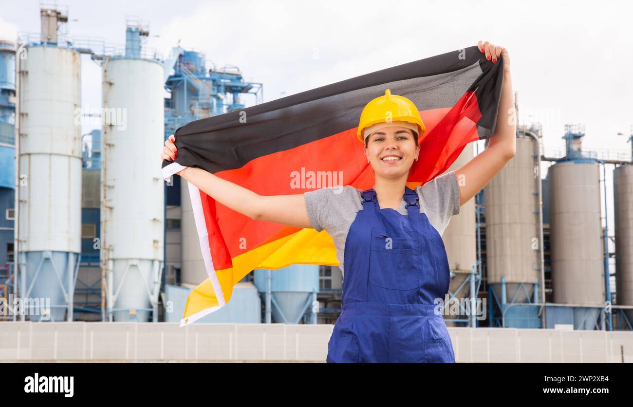 Young female engineer in helmet waving state flag of Germany while ...