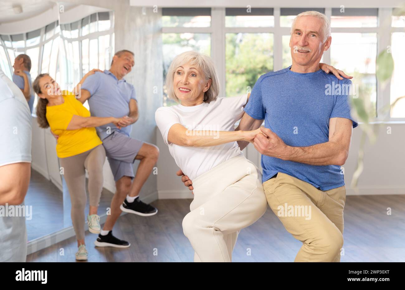 Enthusiastic senior couple practicing jive in group dance class Stock ...
