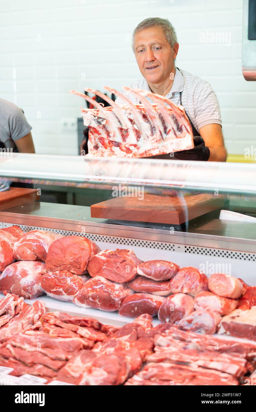 Aged butcher showing slab of raw beef ribs for tomahawk steaks Stock ...