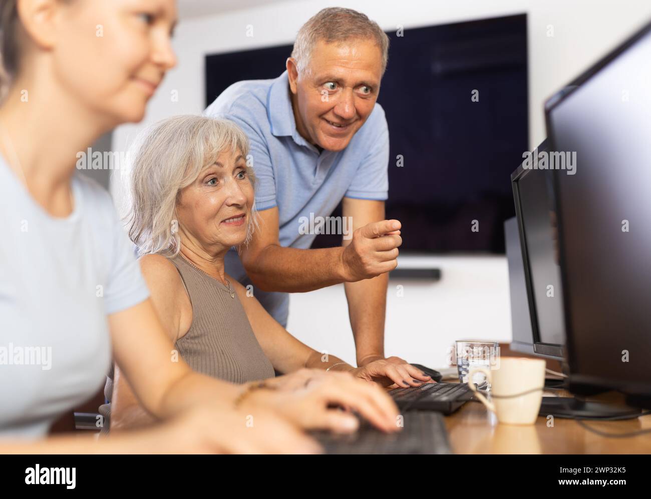 Old woman learning computer programs with teacher in training room ...
