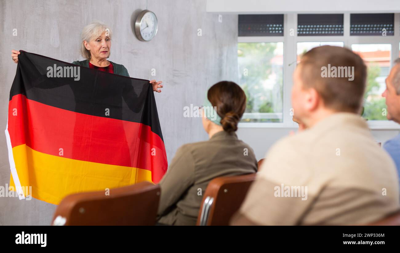 Mature female professor showing german flag to elderly students Stock ...