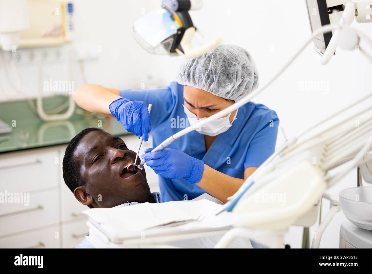 Dentist professional filling teeth for man patient sitting in chair ...