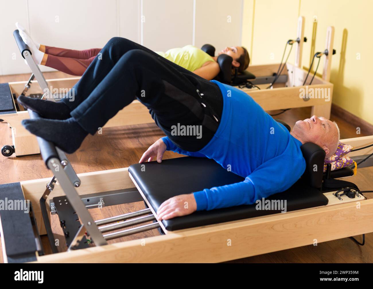Senior man doing stretching exercises on pilates reformer Stock Photo ...