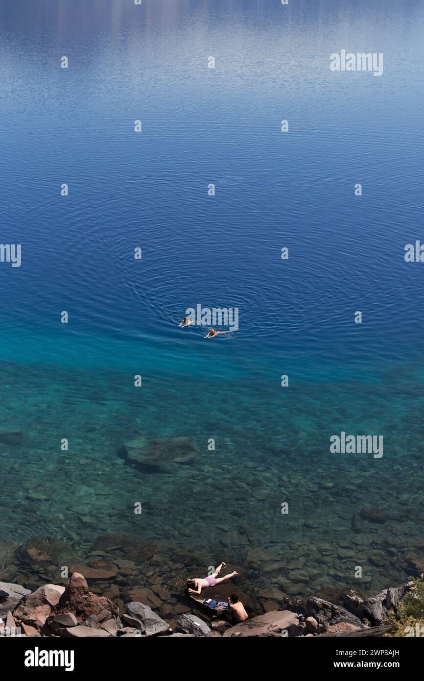Several people swimming in the deep blue water of Crater Lake in Oregon ...