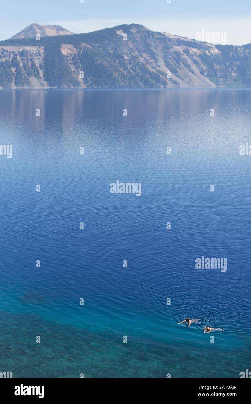 Two people swimming in blue Crater Lake in Oregon, as seen from a ...