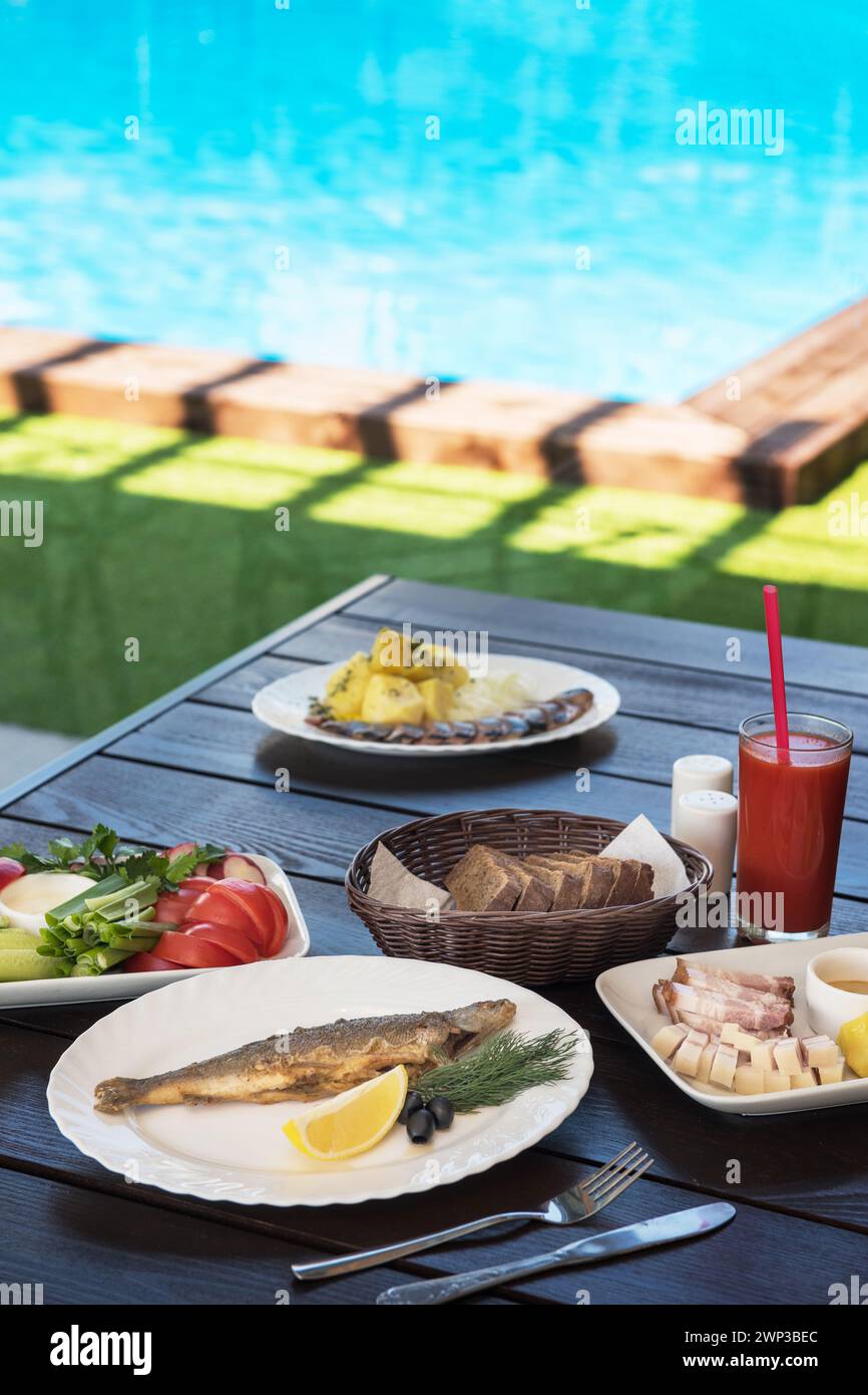 Fried grayling fish on a plate with any appetizers on swimming pool ...