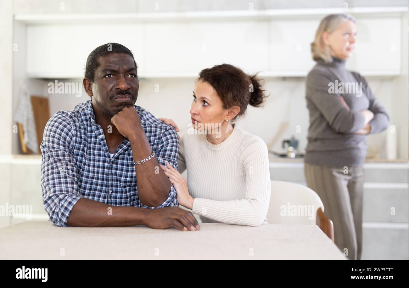Middle-aged woman trying to calm angry man while old woman quarreling ...