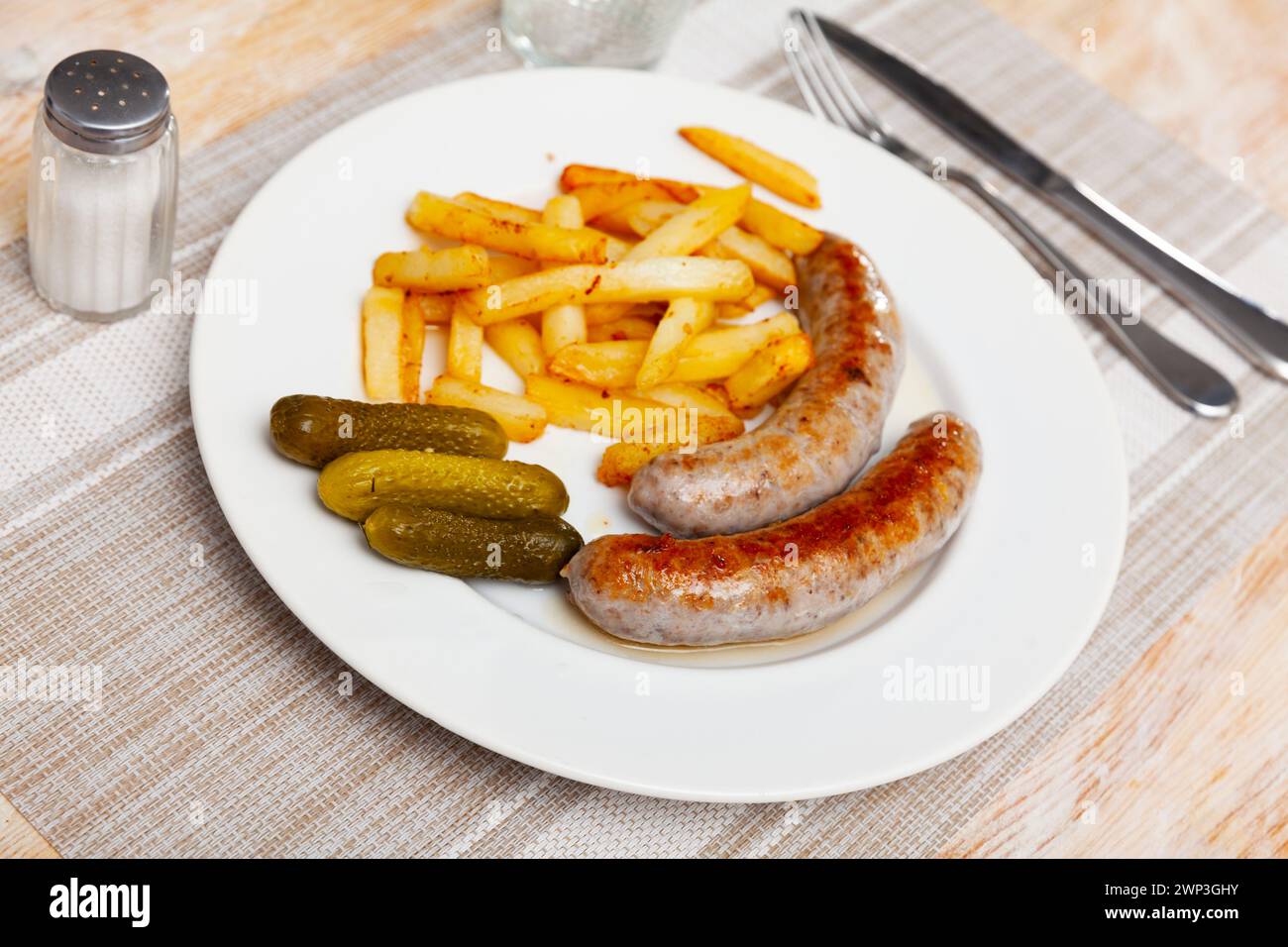 Fried small sausage and french fries, completed with pickled gherkin ...
