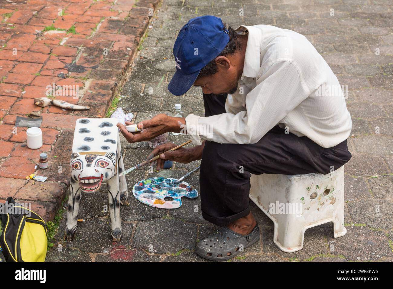 An artist painting a wooden foot stool on the street in the old ...
