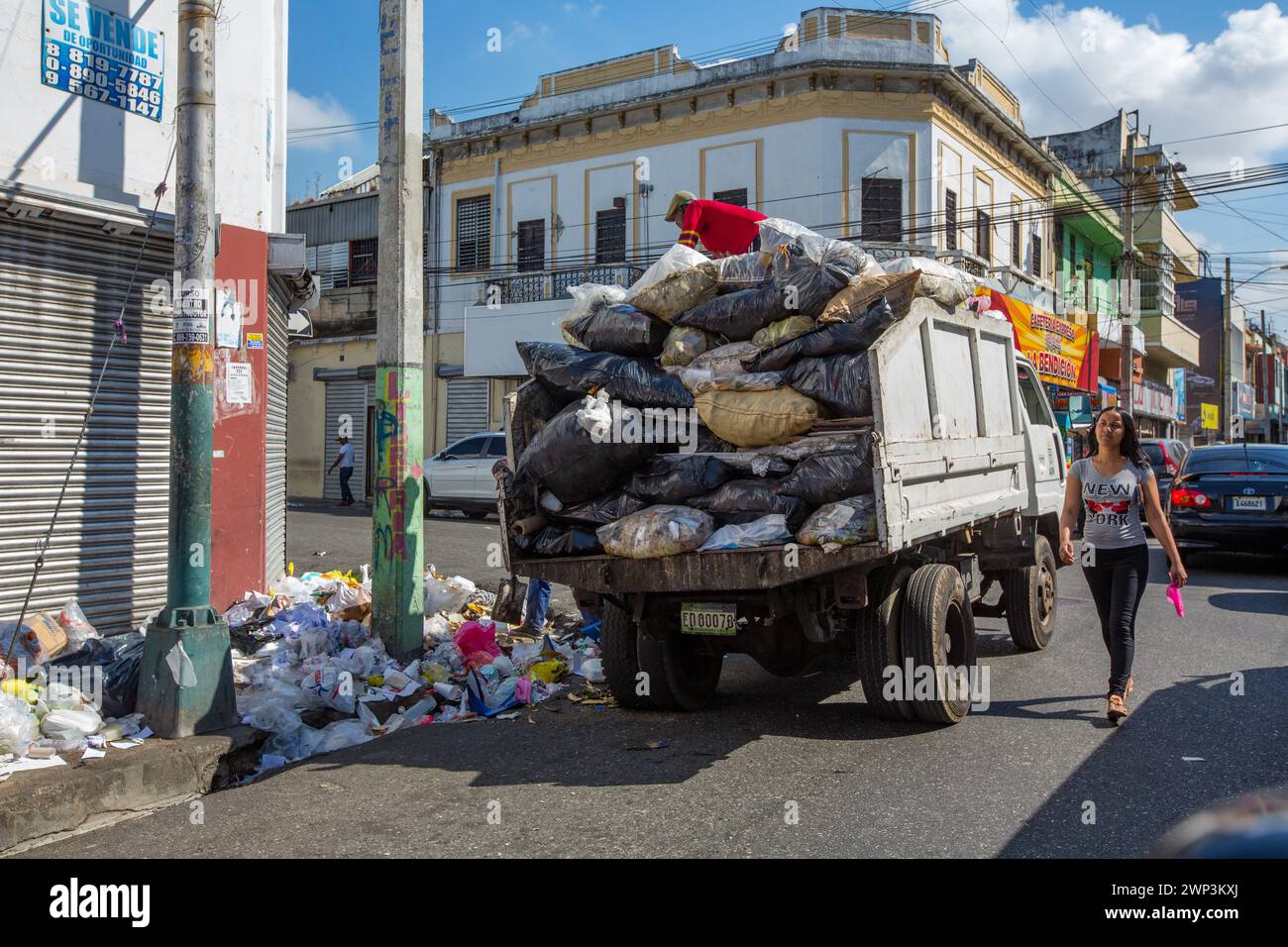 Men load garbage off the sidewalk onto a truck in Santo Domingo ...