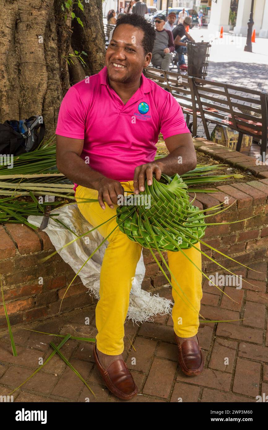 A Dominican man weaves a hat from palm fronds in Columbus Park in the ...
