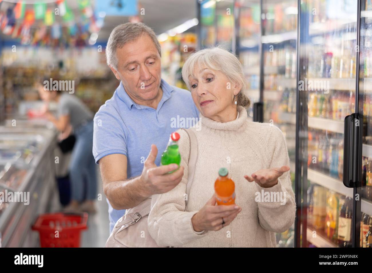 Elderly couple choosing sweet sodas together in the grocery section of ...