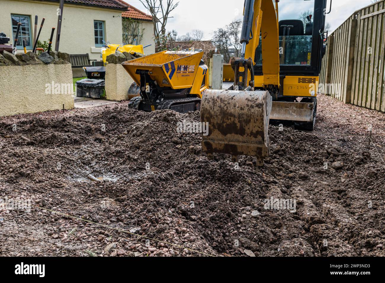 Construction work with a small digger and dumper in driveway to build a ...