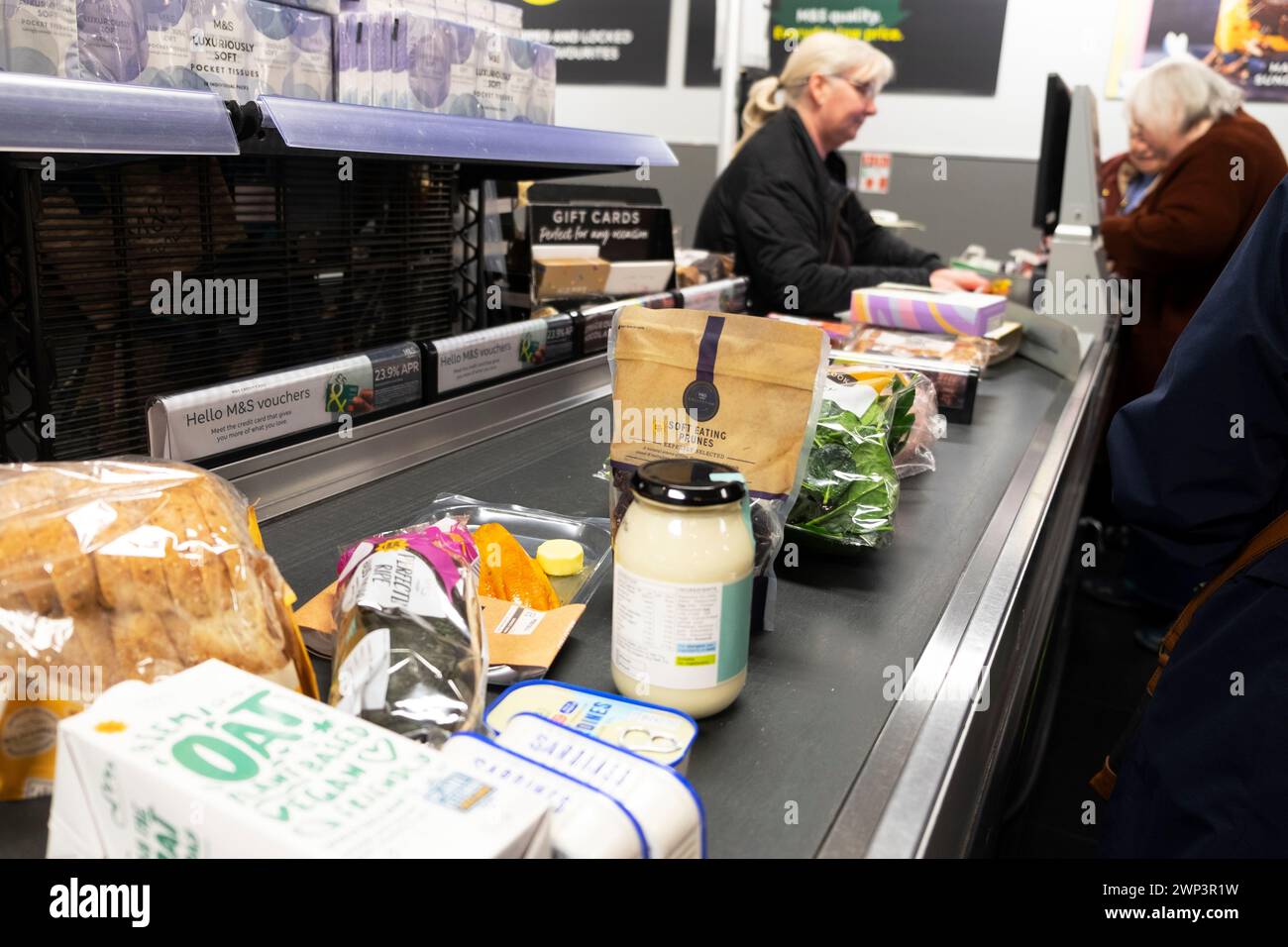 Older woman employee working on till at checkout counter in M&S store ...