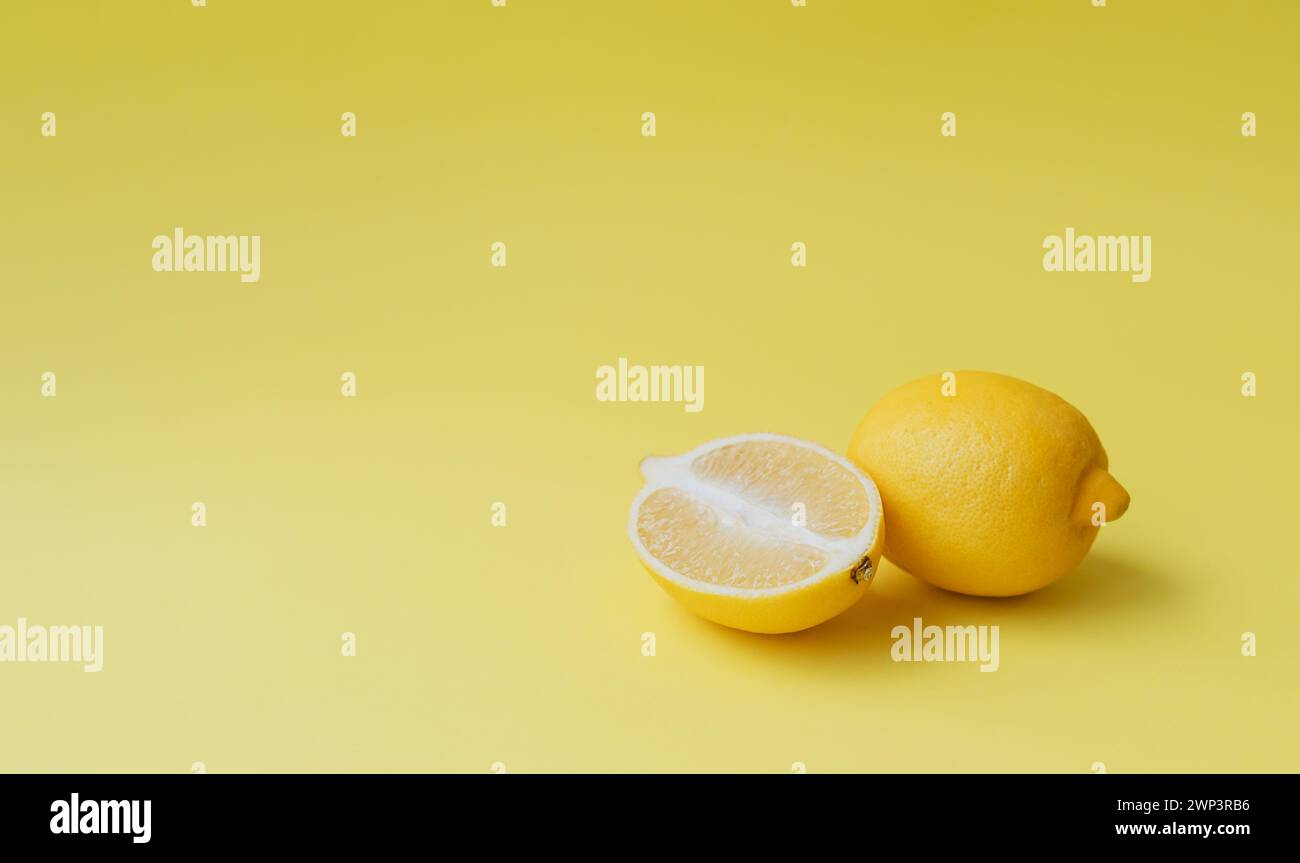 whole lemon and cutted in half one on yellow background Stock Photo - Alamy