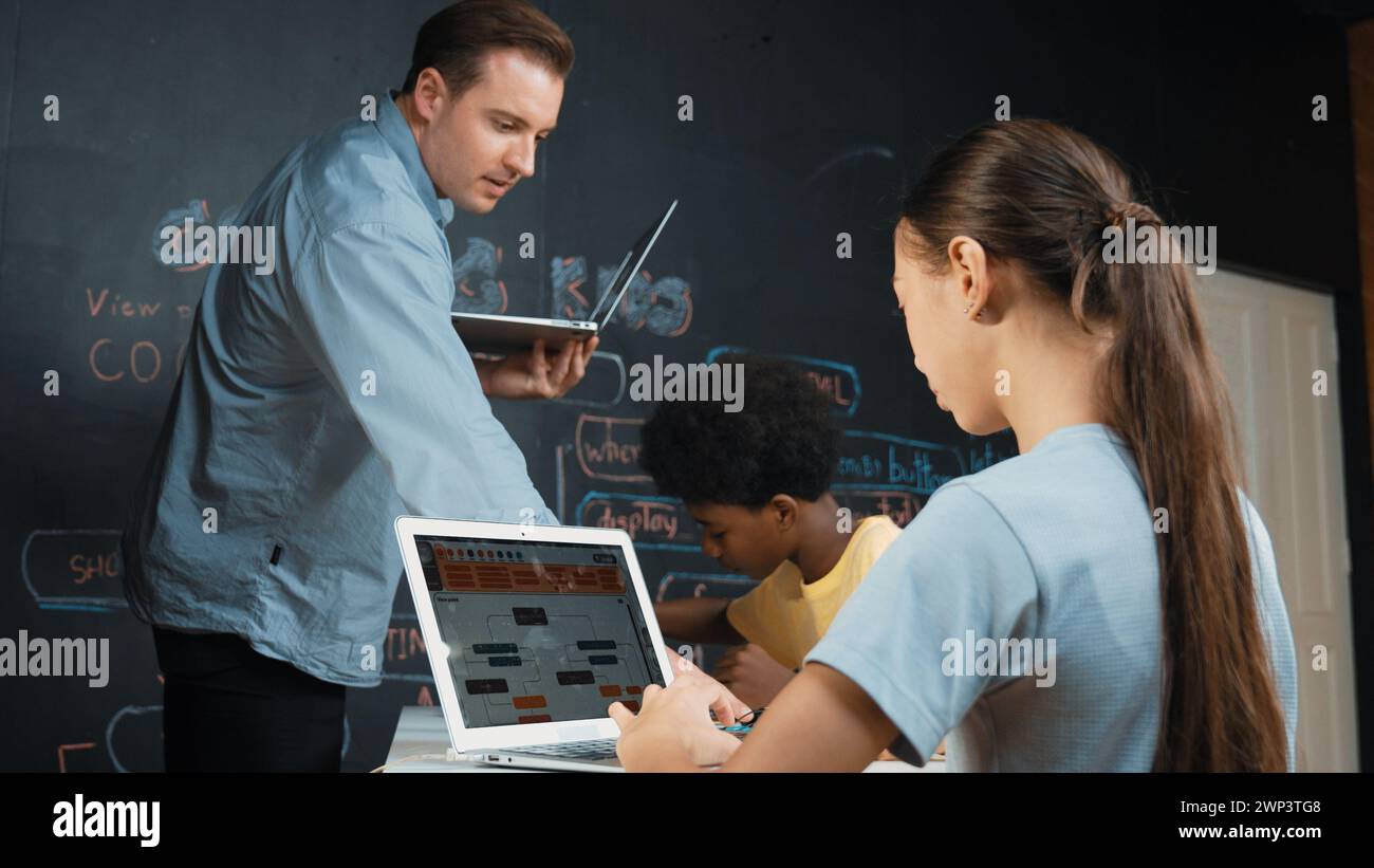 Caucasian girl programing or coding system while african boy fixing model. Teacher holding ...