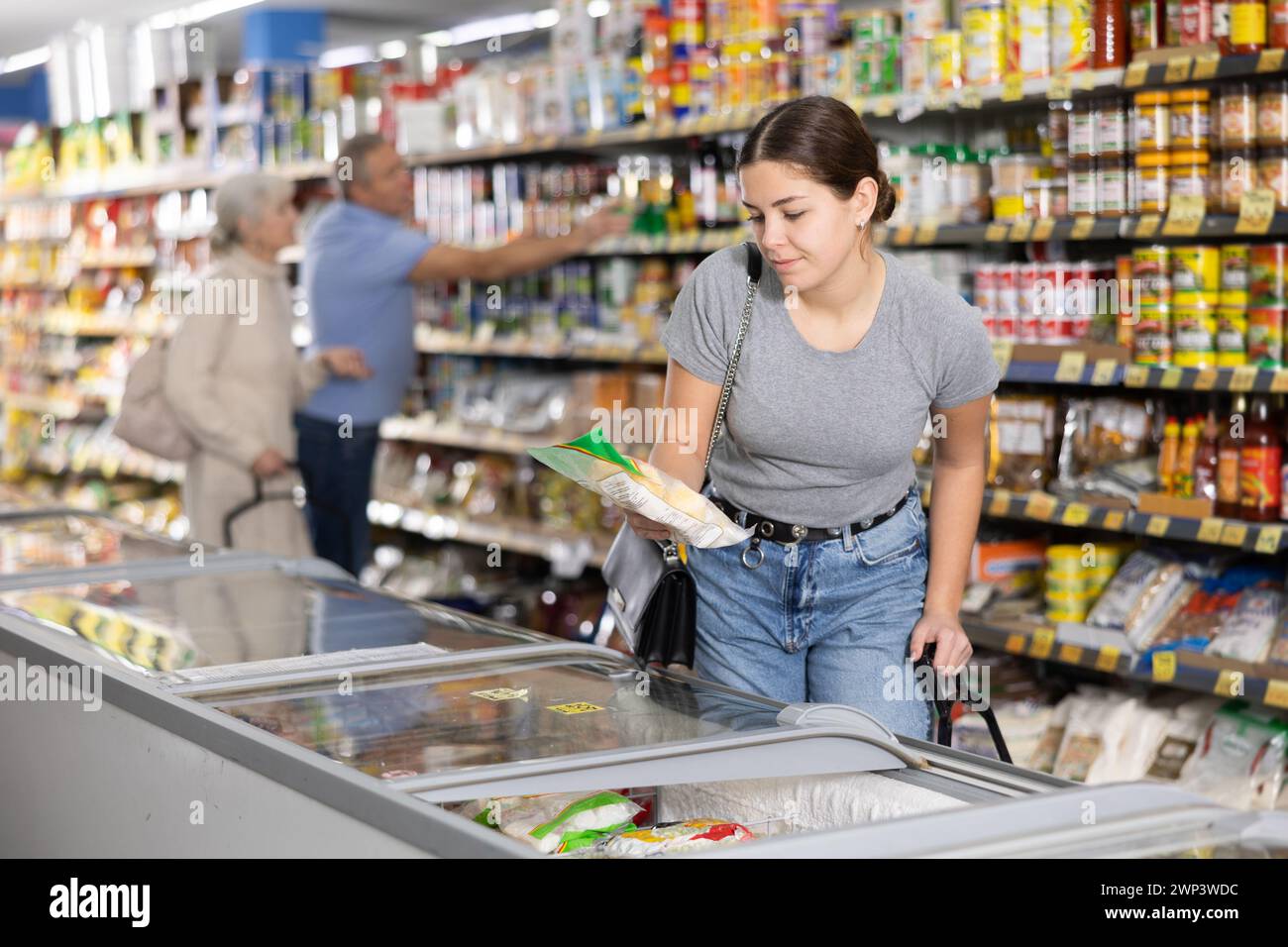 Woman choosing frozen food in supermarket. Woman purchasing goods in ...