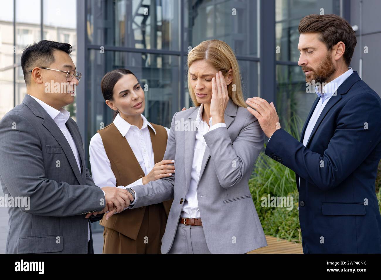 Concerned business colleagues provide comfort to a stressed female ...