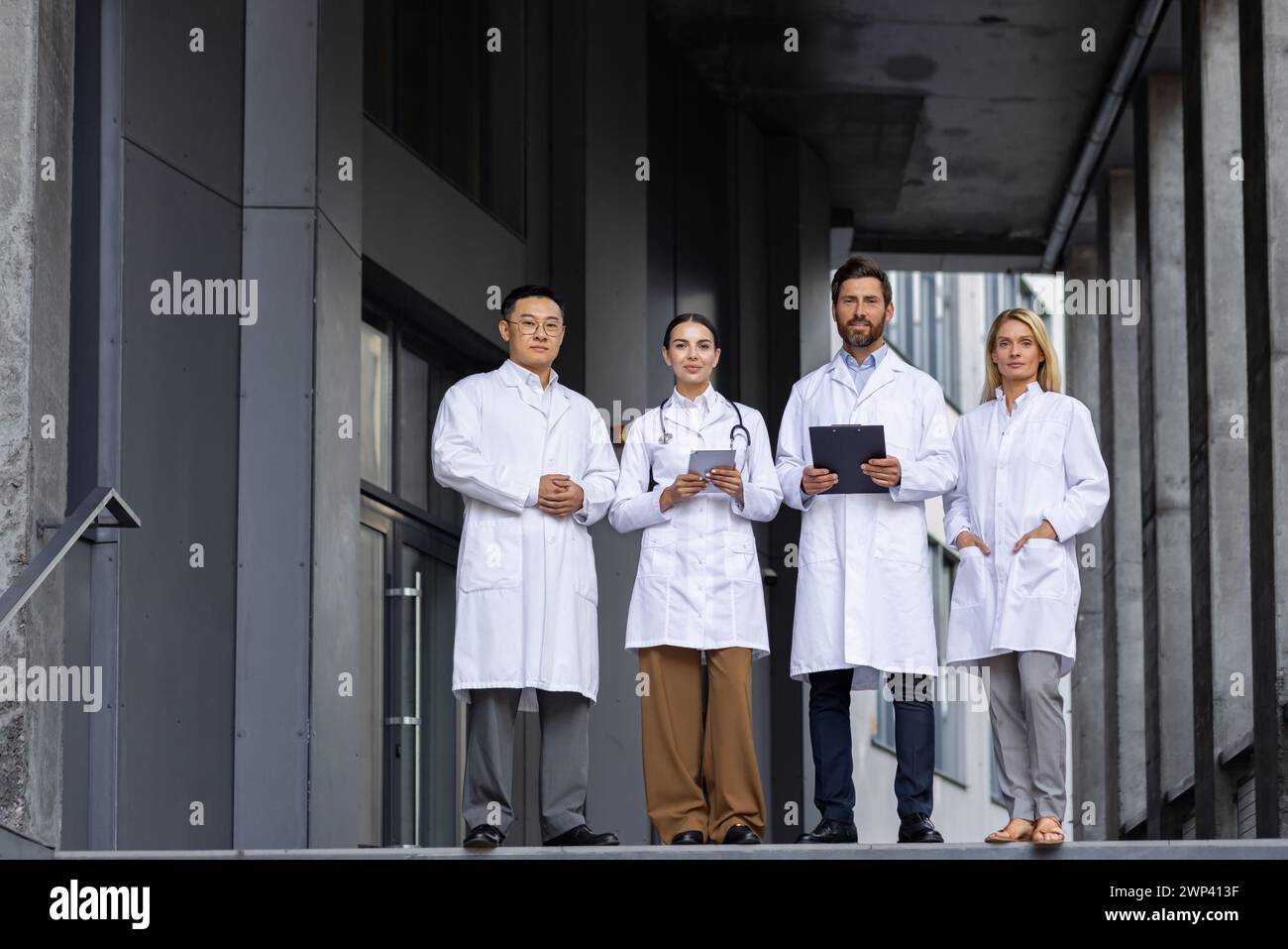 Four medical professionals in lab coats stand confidently on hospital ...