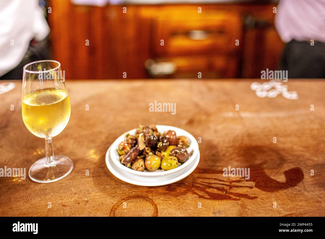 A glass of fino sherry with a side of mixed olives on a bar in a ...
