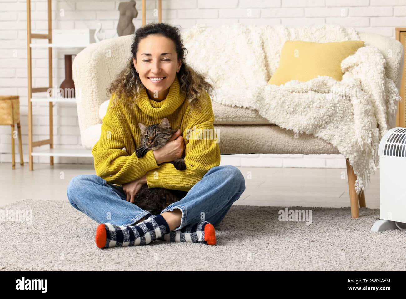 Happy mature woman with cute cat sitting on floor at home Stock Photo ...