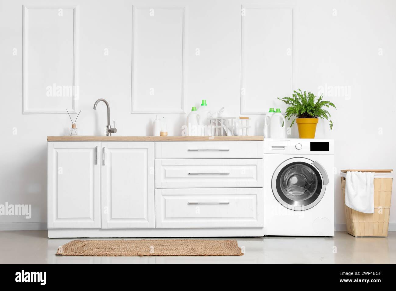 Interior of light room with sink, washing machine and laundry basket ...