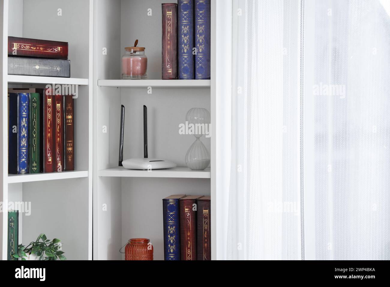 Bookshelf with modern wi-fi router in room Stock Photo - Alamy