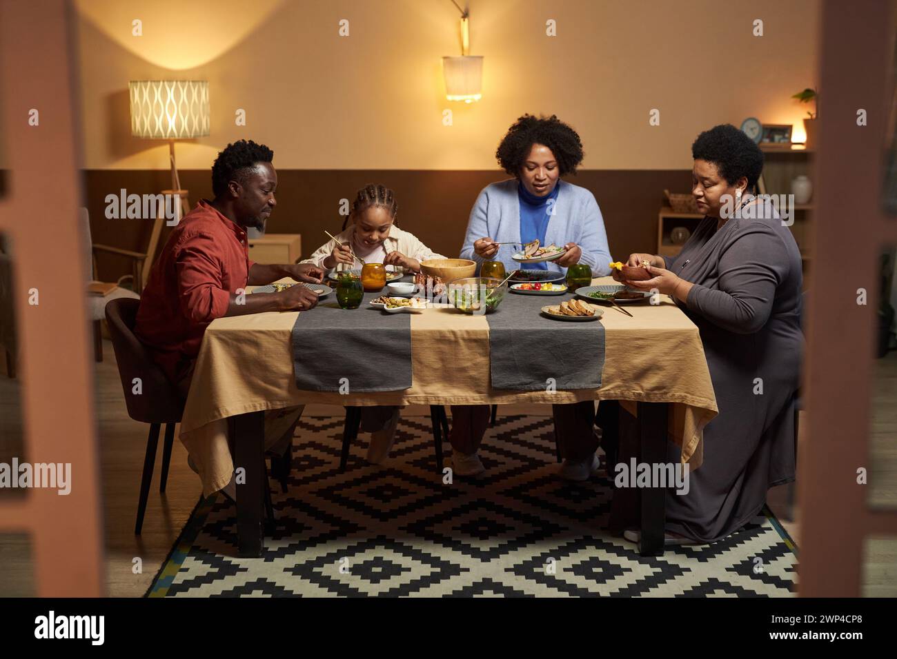 Full length portrait of big African American family sitting at dinner ...