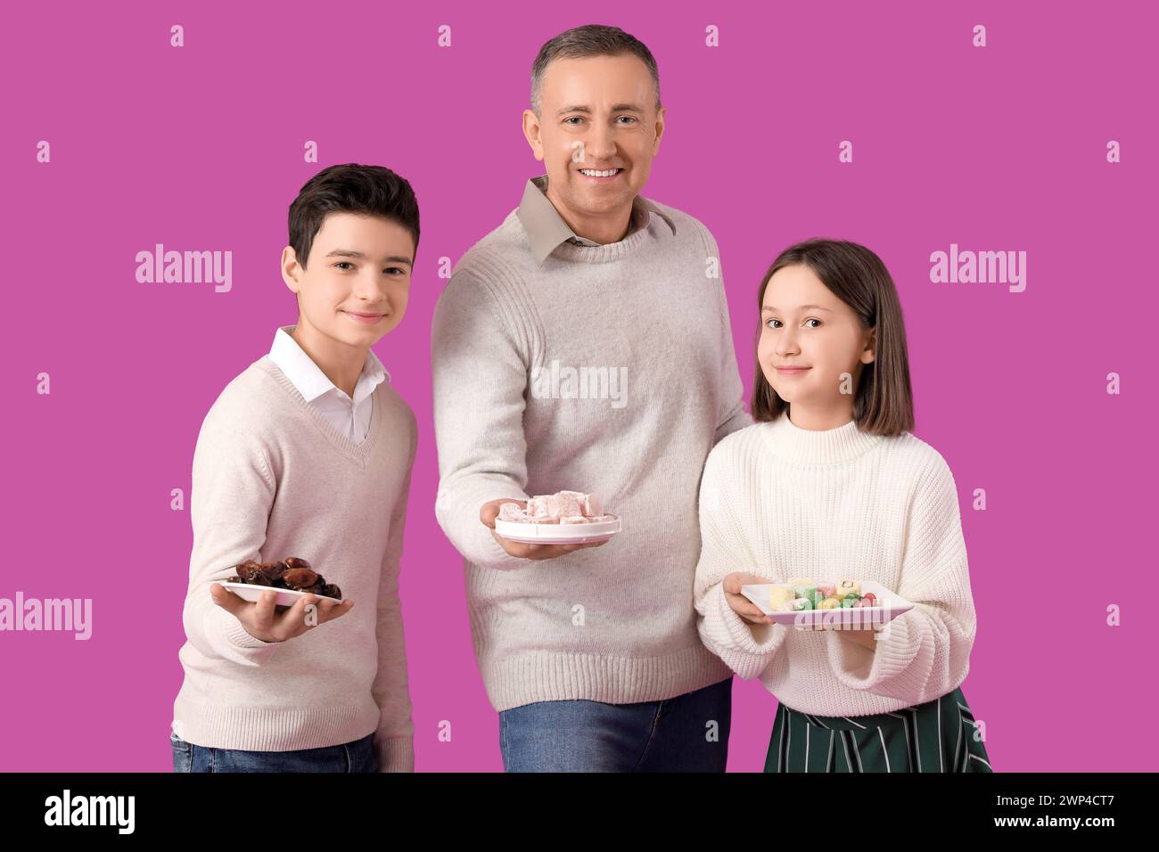 Happy Muslim father and his children with traditional sweets on pink ...